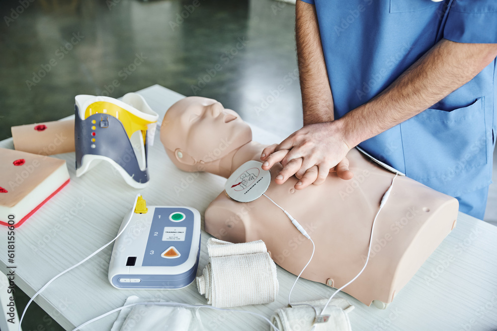 cropped view of paramedic doing chest compressions on CPR manikin near ...