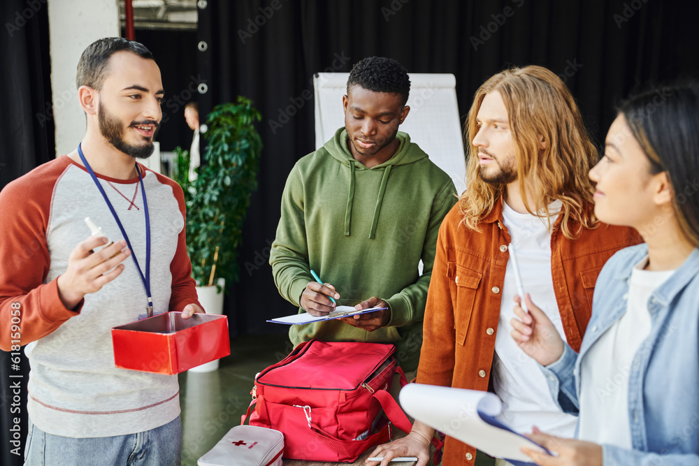 bearded paramedic talking and showing nasal spray and first aid kit to ...