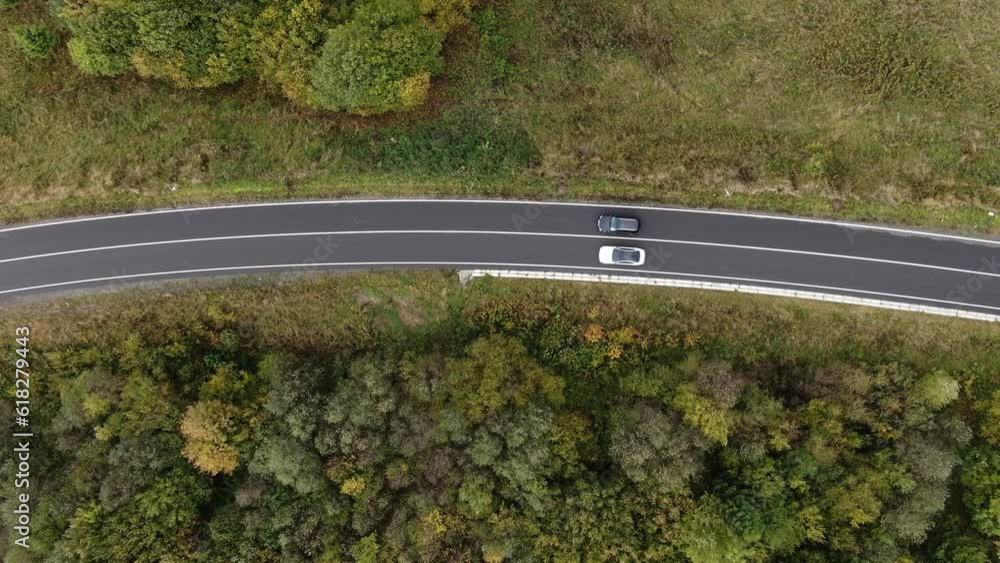 View from above. Cars are driving fast on the road in the autumn forest ...