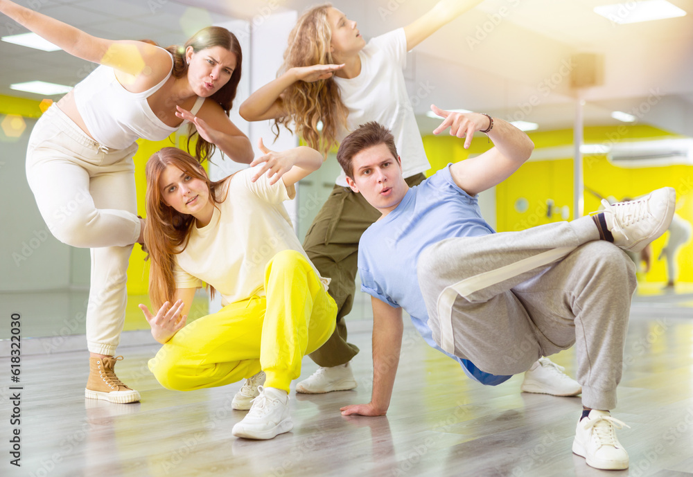 Expressive teenage girls and a boy standing in different breakdance ...