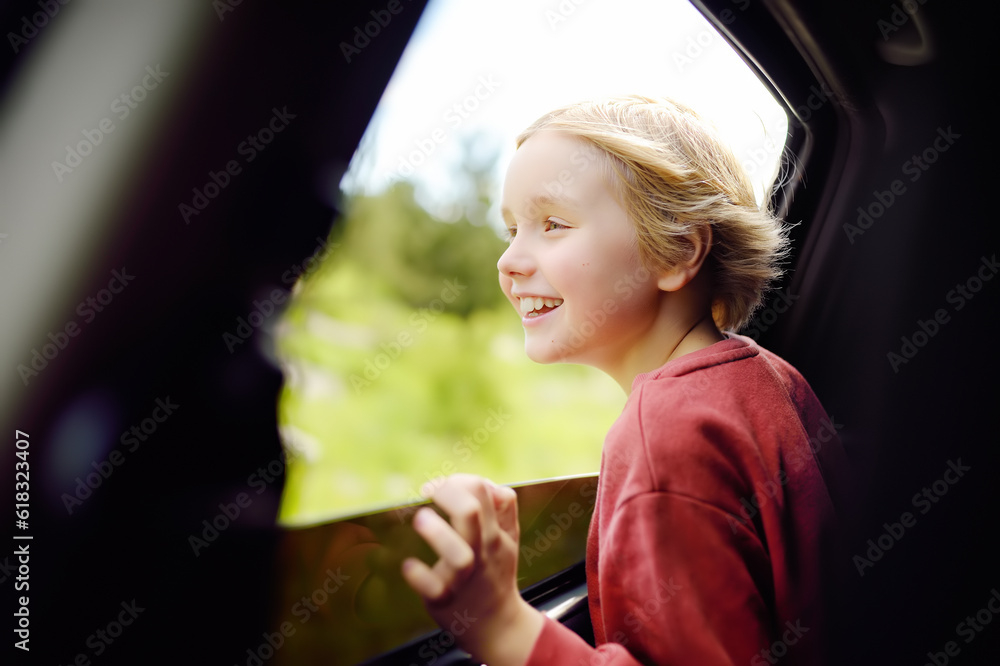Cute preteen boy looking out through window of car during family road ...