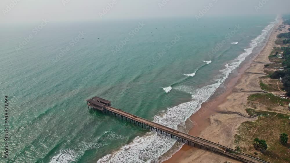 abandoned walking bridge in beautiful beach and houses areal drone shot ...