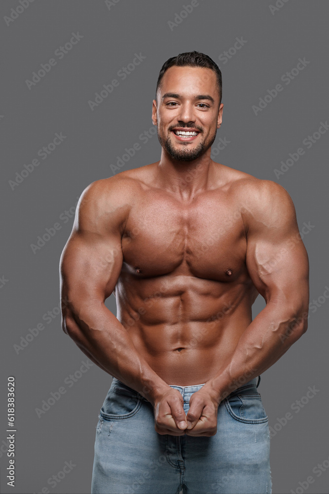 Charming and muscular male model with a dazzling smile poses shirtless ...
