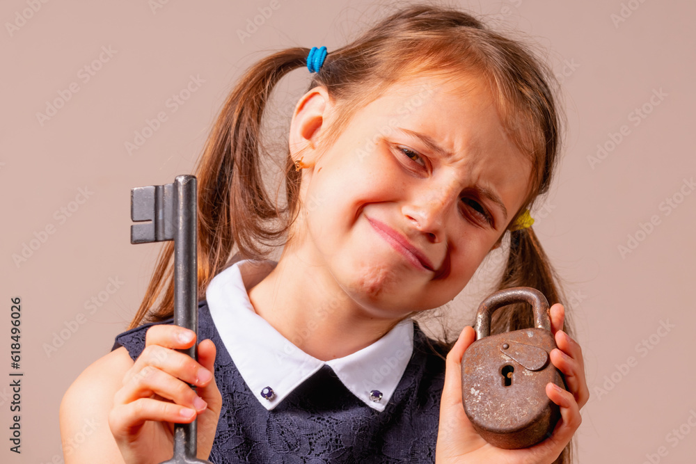 Confused sad beautiful young girl holding big key and small lock as ...