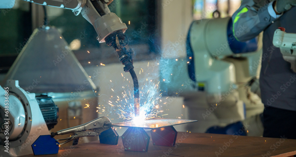 Engineer control robot arm machine welding steel, worker using forcing welding control screen ...