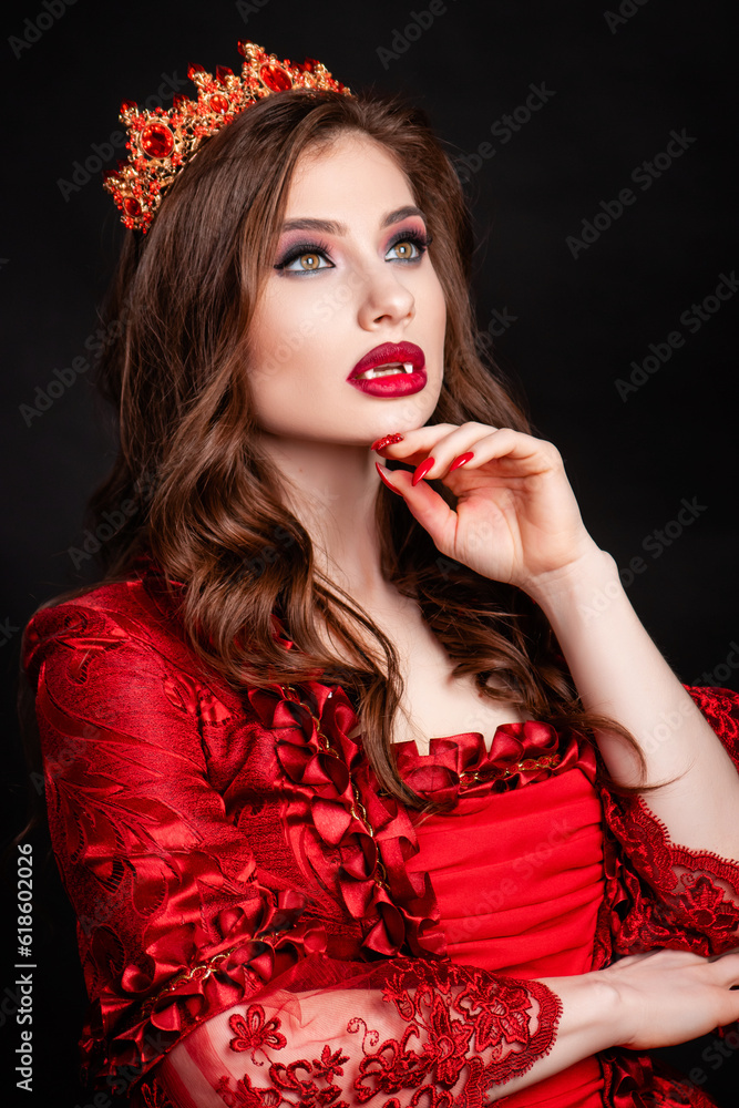 Portrait of a young, attractive vampire woman in a red dress in the ...