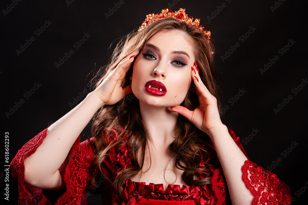 Portrait of a young, attractive vampire woman in a red dress in the ...