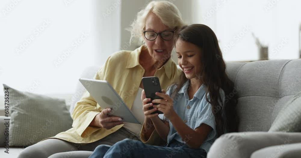 Little girl grandchild helps with modern digital tablet usage to aged ...