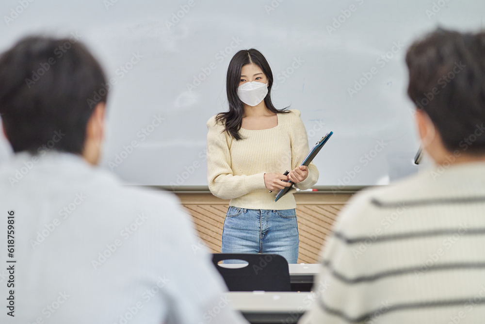 An Asian female student or professor is wearing a mask and standing in ...