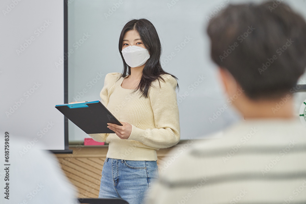 An Asian female student or professor is wearing a mask and standing in ...