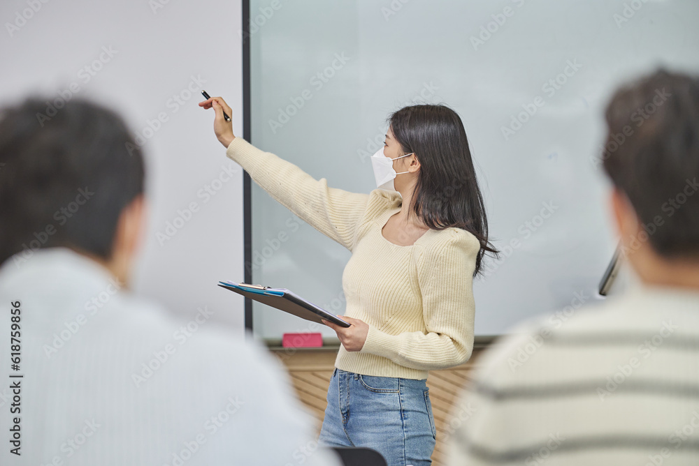 An Asian female student or professor is wearing a mask and standing in ...