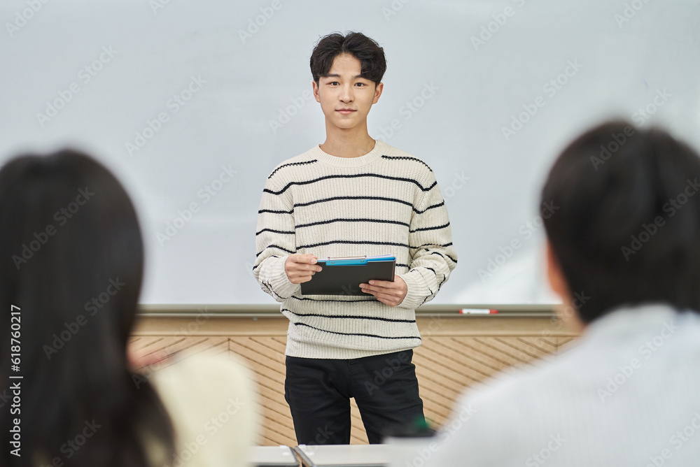 An Asian young man is standing in front of a lecture hall at a ...