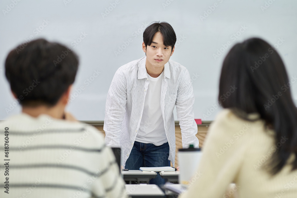 An Asian young man is standing in front of a lecture hall at a ...