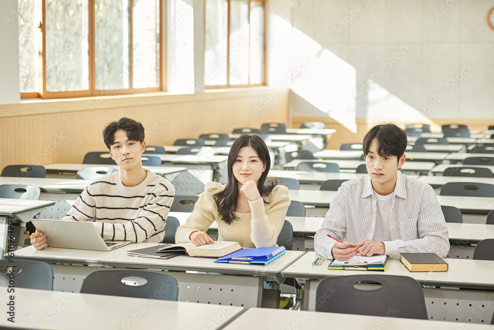 Three young Asian college students, both male and female, are in a ...