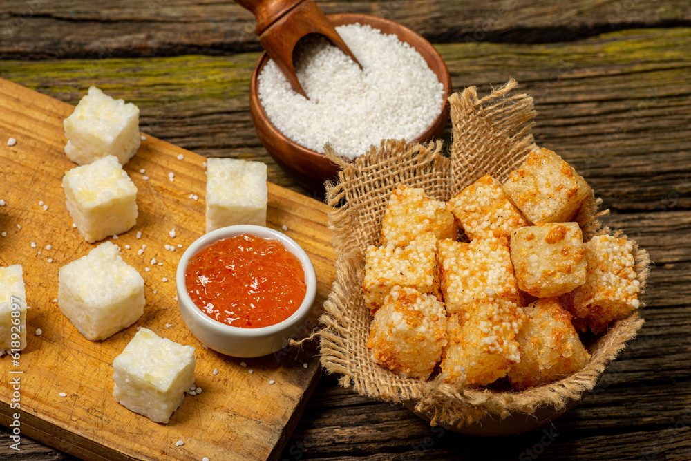 Raw and fried tapioca cubes (Dadinhos de Tapioca) on top of rustic ...
