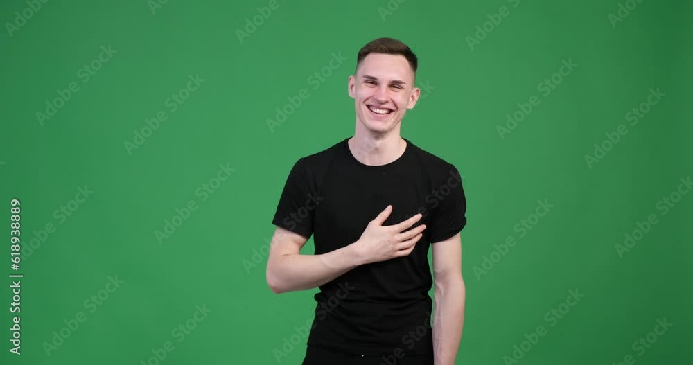 A joyful Caucasian man with a contagious smile stands against a green ...