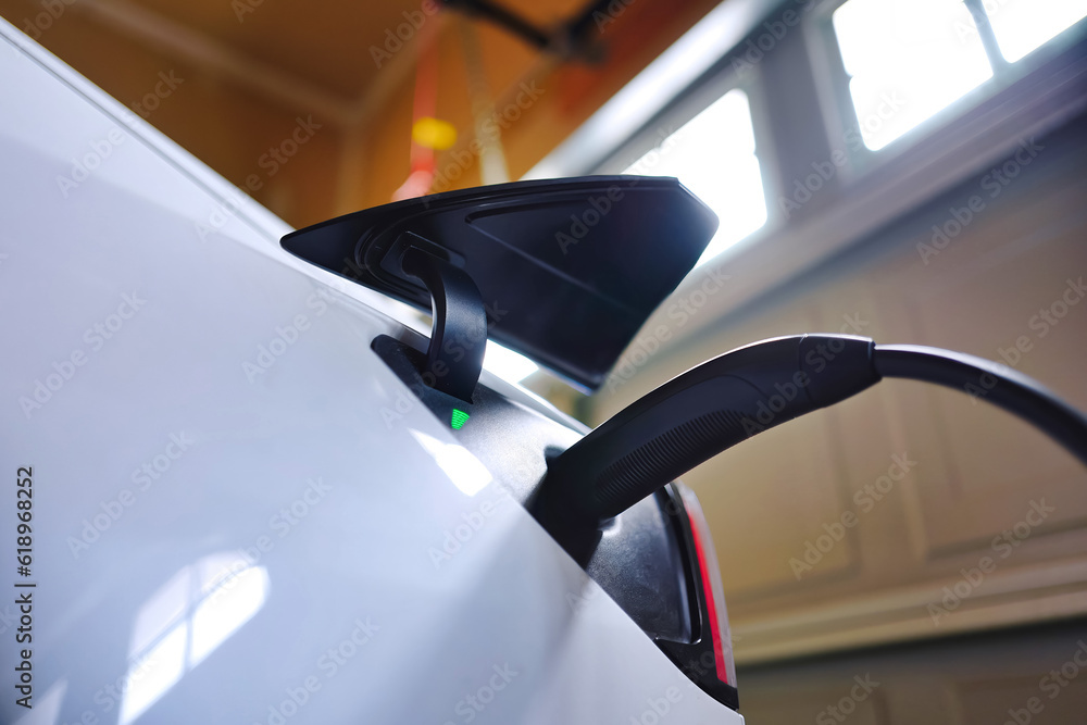 White EV electric car plugged and charging inside garage at home with ...