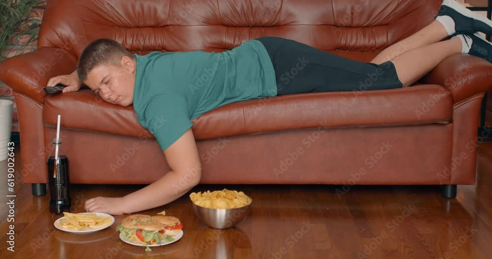 Vidéo Stock Obese boy is sleeping on sofa, waking up, drinking coca ...