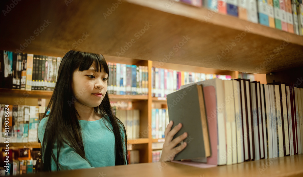 Little girl choosing book in public library room selecting literature ...