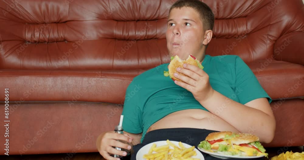 Fat teenager boy eating hamberger fast food . Breakfast for overweight ...