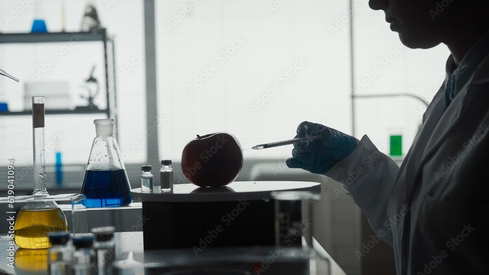 Dark silhouette of a female scientist with a syringe in her hand in a ...