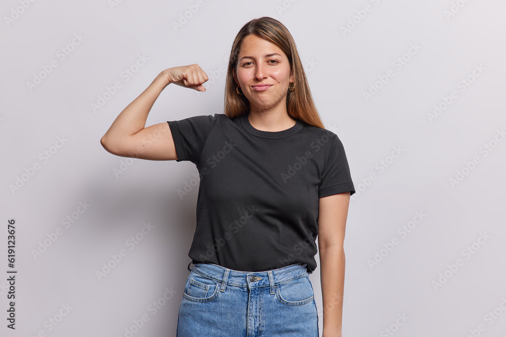 Womens power. Serious young European woman raises arm and shows muscle ...