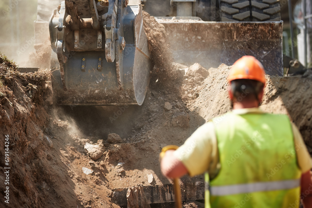 A worker wearing a helmet and reflective vest inspects the ongoing ...