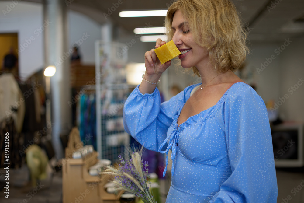 Cheerful young woman sniffing a handmade soap bar in a store. Portrait ...
