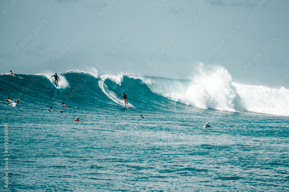 Two Surfer girls on long boards on perfect blue aquamarine wave ...
