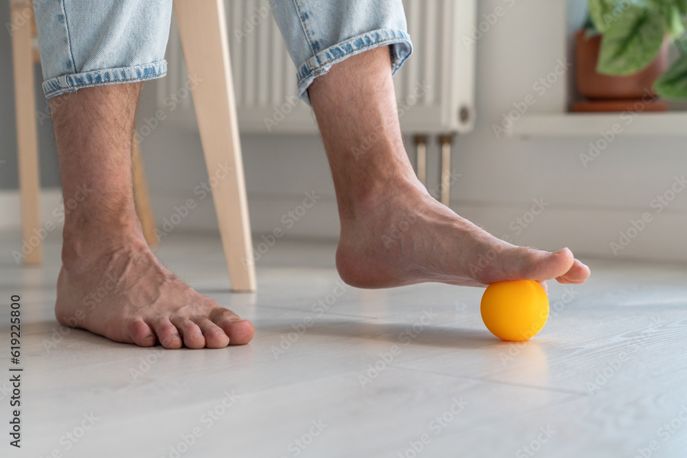 Man using silicone ball for foot massage during long sedentary work ...
