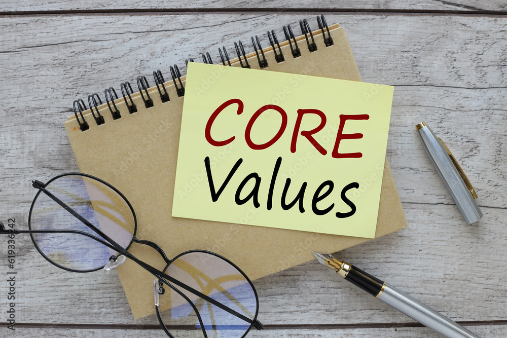 core values text on a yellow sticky note on the desk next to the glasses. Stock Photo | Adobe Stock
