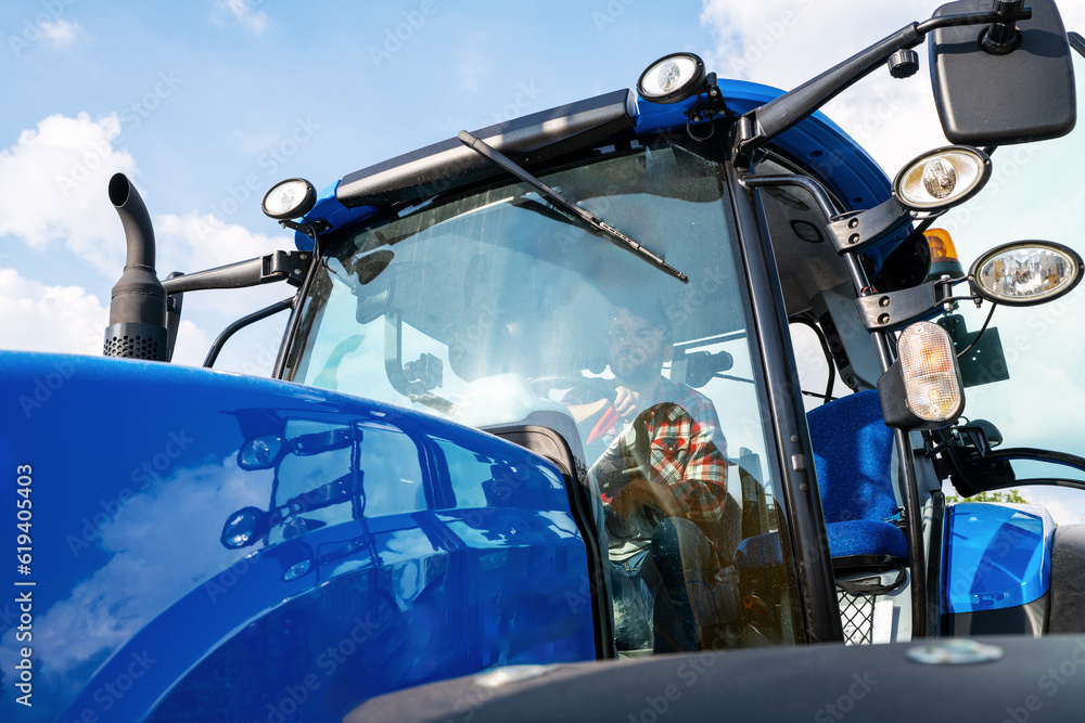 Cabin and windshield of agriculture tractor and tractor driver behind ...