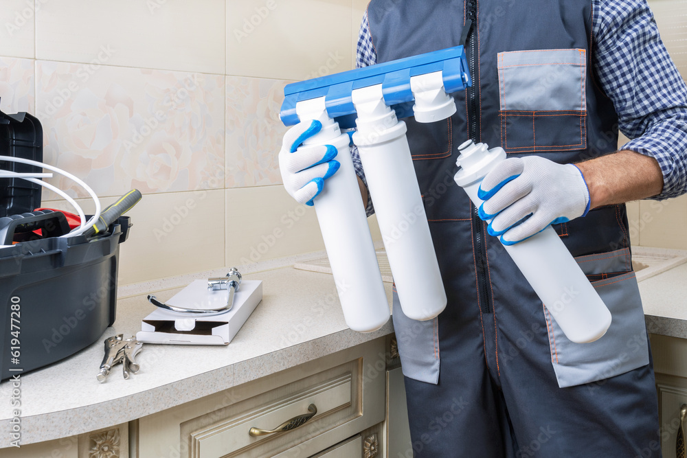 Plumber man installs or change water filter in the kitchen. Stock Photo ...