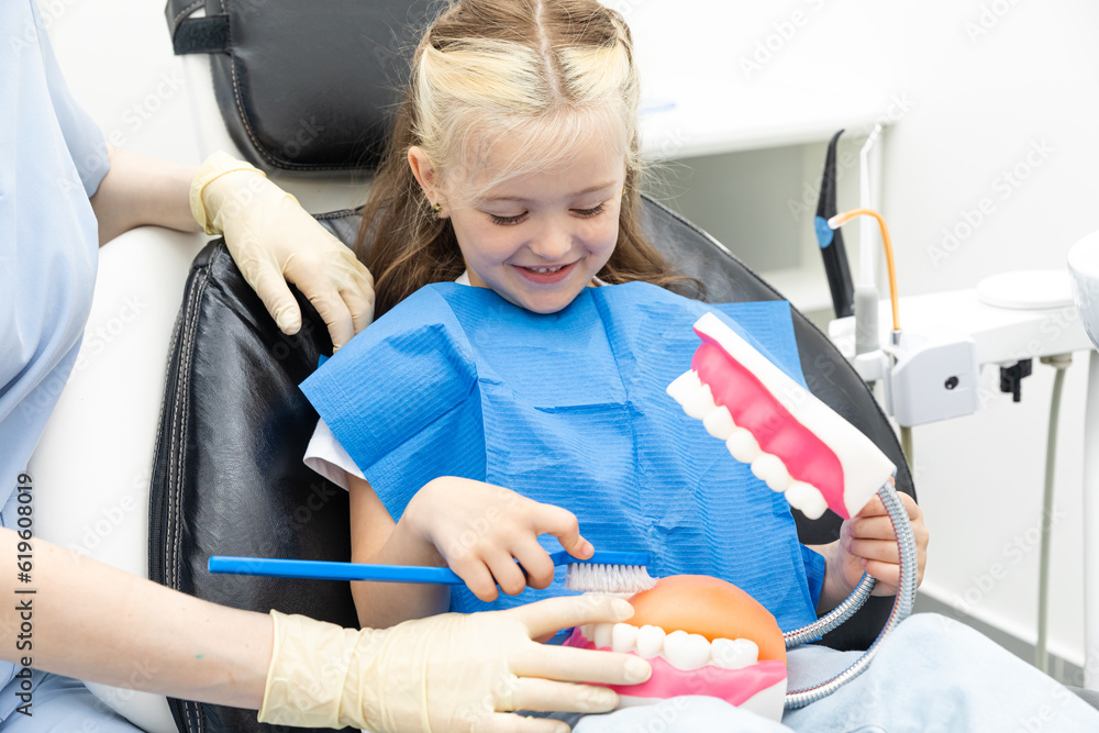 Little child in dentists surgery learning how to brush teeth with giant ...
