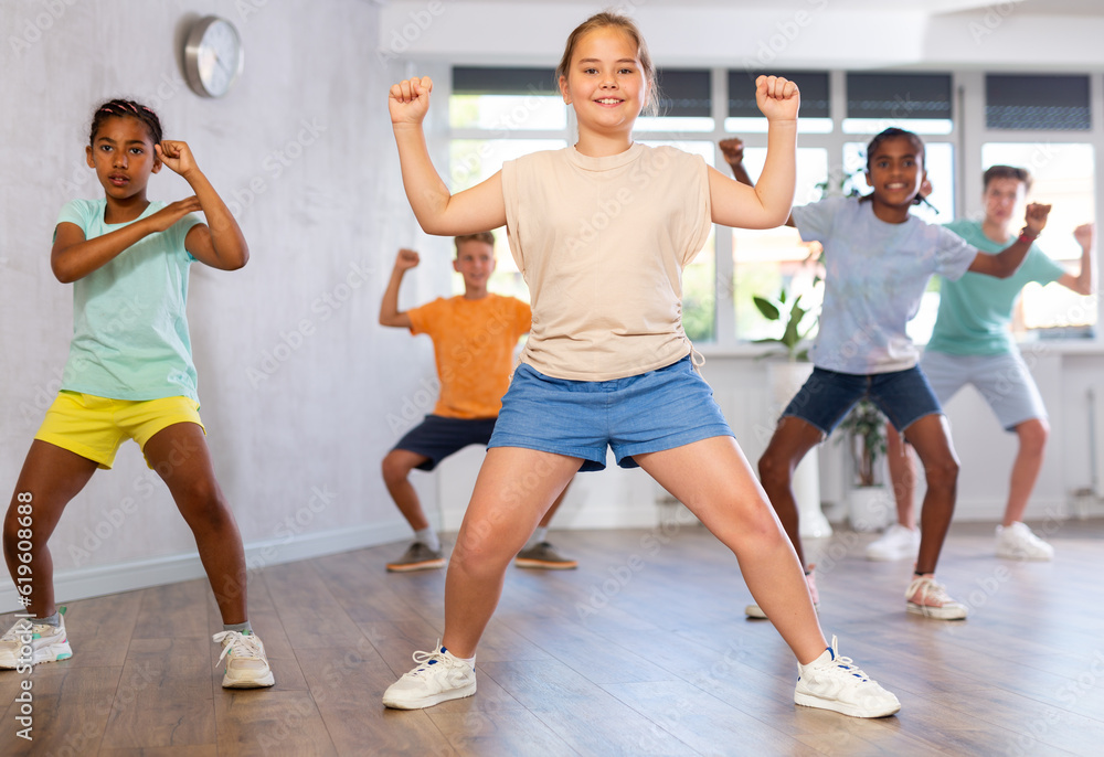Portrait of cheerful preteen girl enjoying modern dancing during group ...