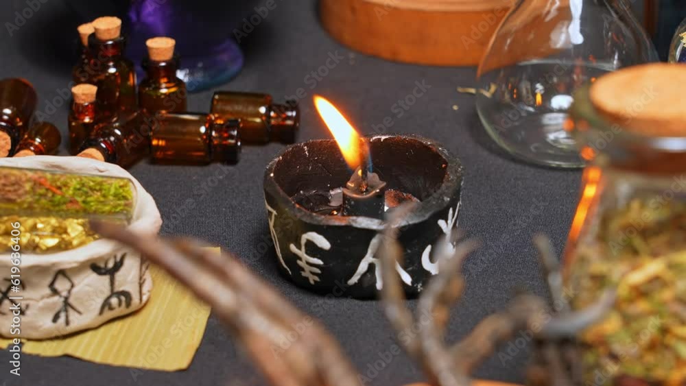 Witchcraft still life focus shift with black burning candle in the cup ...