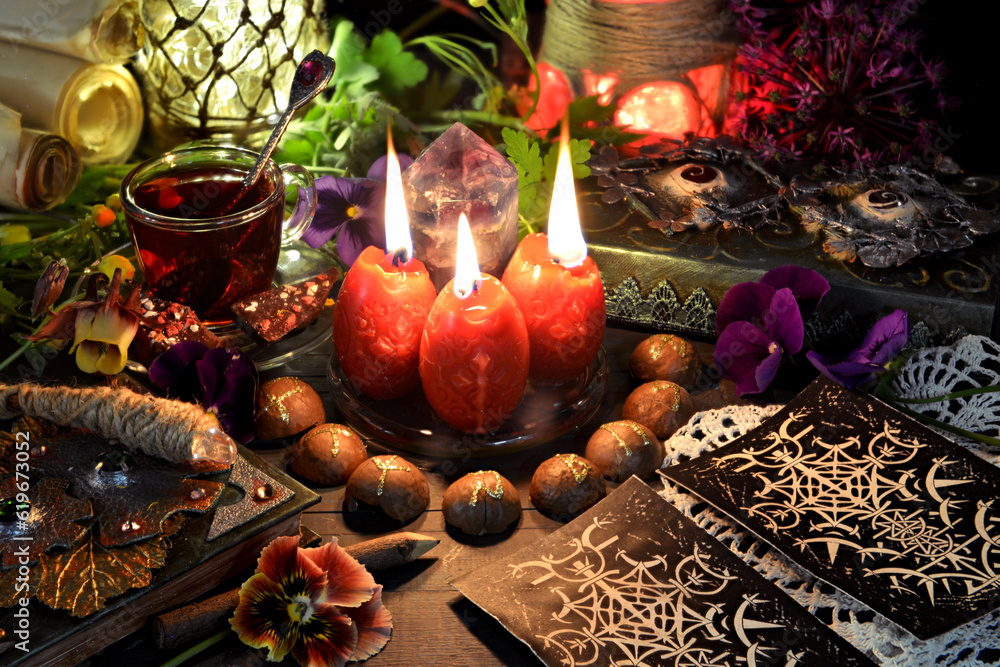 Still life with tarot cards, red candles, magic wand and book of spells ...