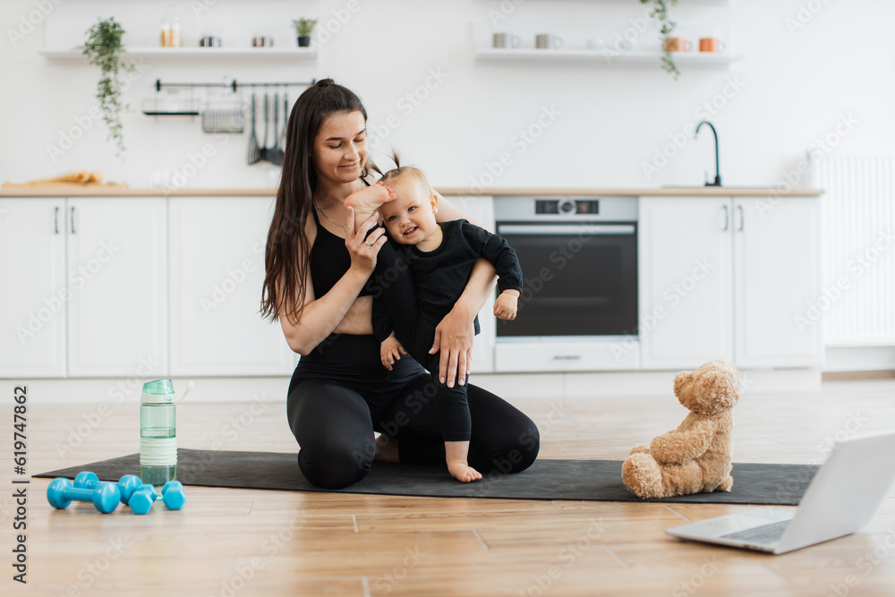 Adorable little child doing splits with mother's support while ...