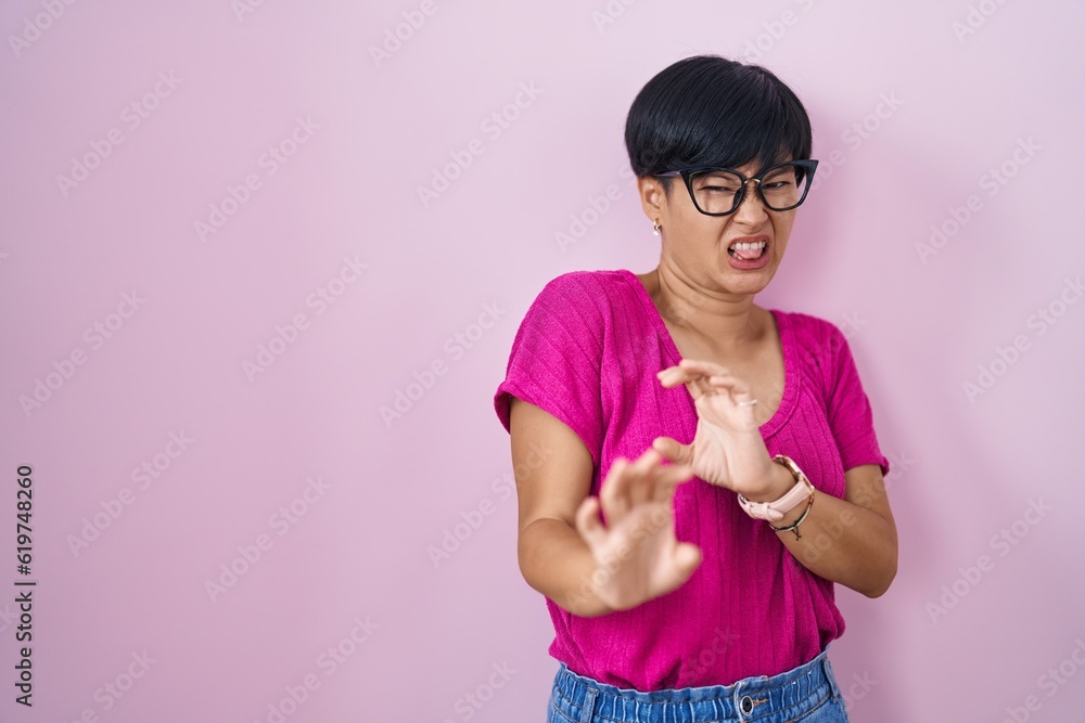 Young asian woman with short hair standing over pink background ...