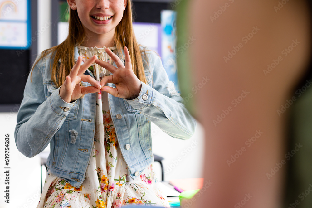Happy diverse schoolchildren using sign language in school classroom ...
