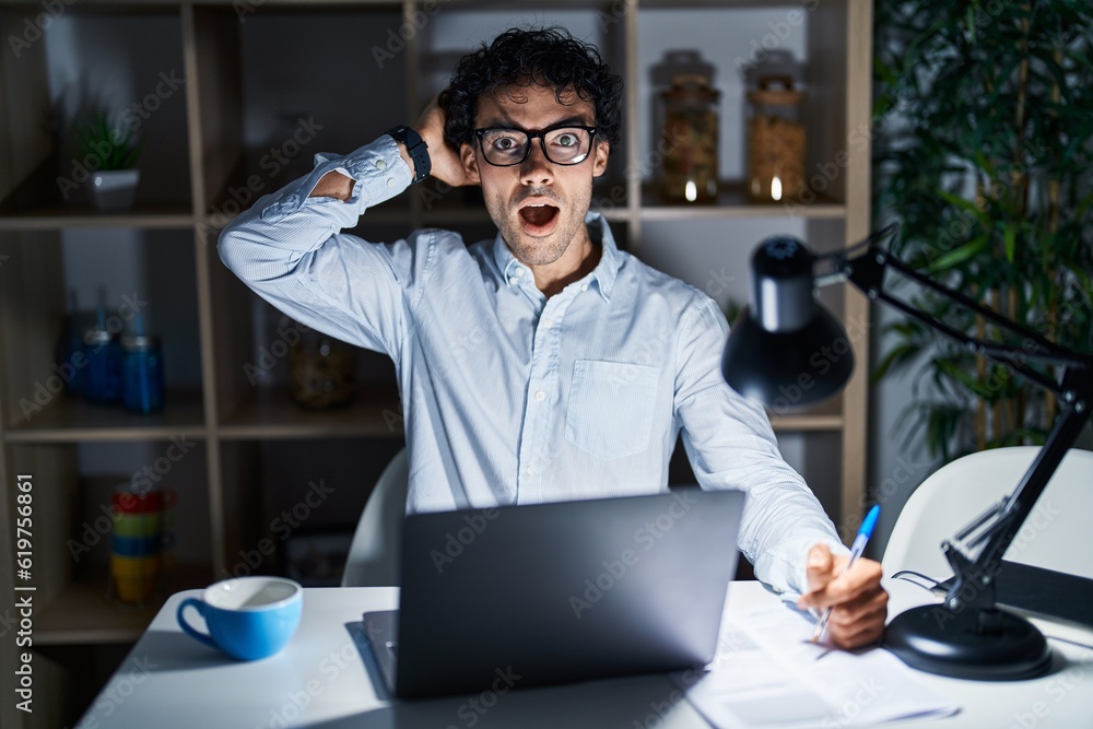 Hispanic man working at the office at night crazy and scared with hands ...