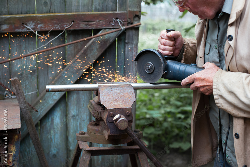 old man working. Cutting a metal pipe. spark. the pipe is clamped in a ...