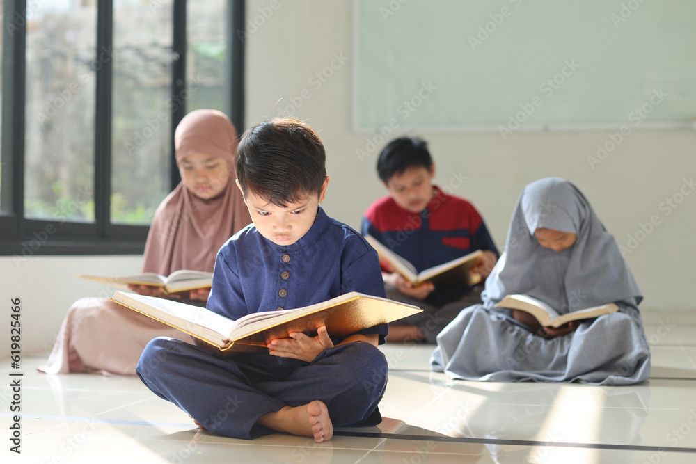 Selective focus of Muslim children reading Koran or Quran together ...