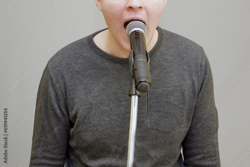 Young man's mouth wide open in front of a microphone. Loud shouting ...