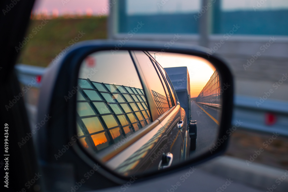 View in the mirror of the side view of the car on the road and caravan ...