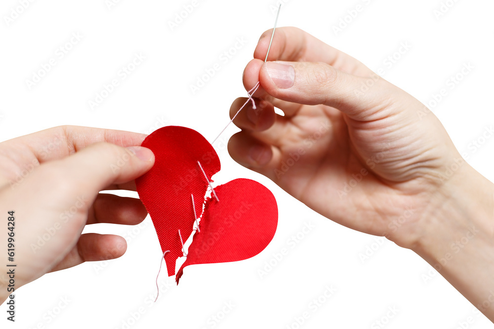 Hands repairing a broken red heart using needle and thread, cut out ...