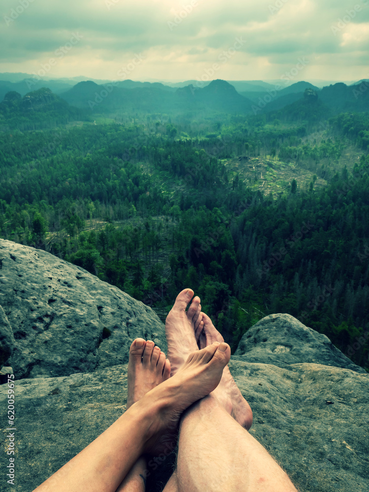 Crossed bare legs of a heterosexual couple cuddling on a cliff. Park ...