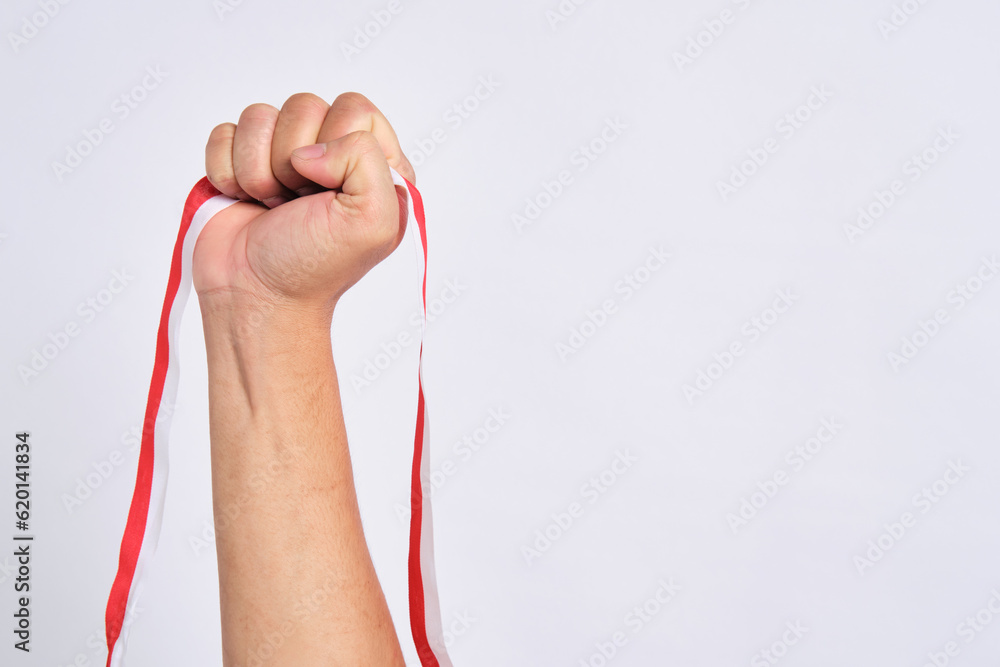 Human hand holding a red and white ribbon as a symbol of the Indonesian ...