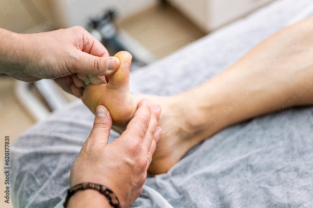 An unrecognizable podiatrist is checking an athlete's foot in a modern ...