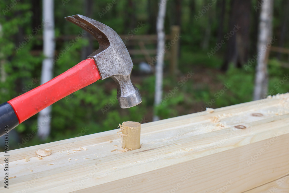 hammer strikes wood dowel to secure connection of wall timbers ...
